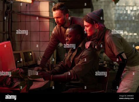 Group Of Three Diverse People Surviving Apocalypse Checking Data On Old Computer In Abandoned