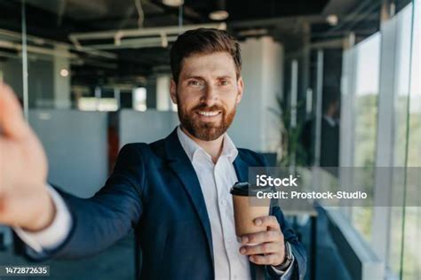 화상 통화를 하고 커피를 마시고 현대적인 사무실에 서서 카메라를 향해 웃고 있는 행복한 사업가 30 39세에 대한 스톡 사진 및