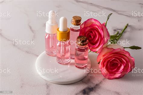 화장품 장미 오일과 장미 물은 장미가 있는 흰색 둥근 대리석 연단에 다양한 유리병에 담겨 있습니다 천연 화장품 추가 치료 강단에