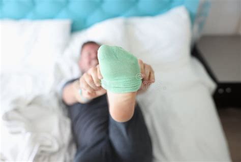 Homme Allongé Sur Le Lit Et Mettant Sur La Chaussette Verte Photo stock