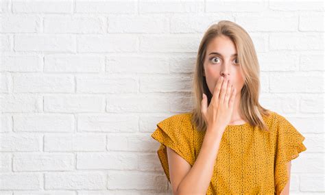 침묵 비밀 개념에에서 무서 워 하는 백색 벽돌 벽 커버 입 손으로 실수 두려움의 표현에 대 한 수치와 충격에 아름 다운 젊은 여자 가리기에 대한 스톡 사진 및 기타 이미지