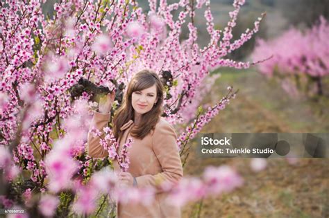 귀여운 아름 다운 세련 된 옷을 입고 갈색 머리 소녀 핑크 꽃 봄 어린 복숭아 나무의 분야에 서 있는 어머니 엄마와 함께 레이디