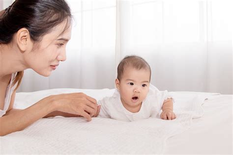아름다운 젊은 엄마와 유아가 침실에 누워 함께 이야기하거나 노래합니다 싱글맘은 귀여운 신생아와 놀고 침대에서 함께 시간을 보내고