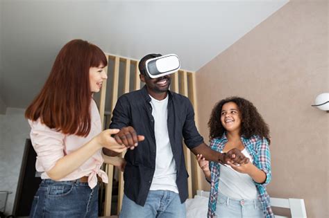 잘 생긴 젊은 즐거운 아프리카 남자 아버지 Vr 헤드셋을 시도 그의 예쁜 백인 아내와 귀여운 십대 혼합 인종 딸의 손을 잡고 가상현실에 대한 스톡 사진 및 기타 이미지