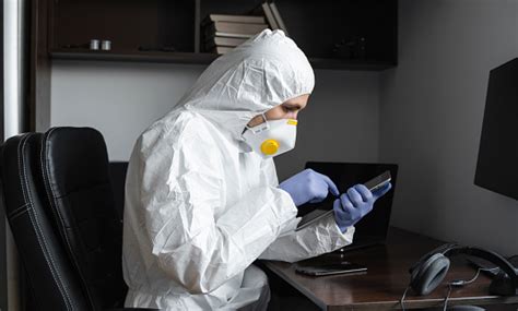 보호복 의료용 마스크 고무 장갑을 착용한 남자가 집에 앉아 검역 중에 태블릿과 함께 작업합니다 디자이너 예술가 건축가 전염병 의