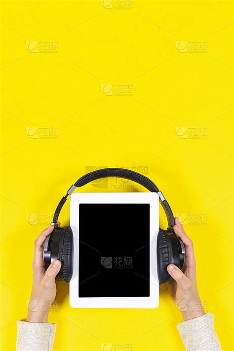 在线学习，远程教育理念。孩子的手拿着数字平板电脑与耳机在黄色背景