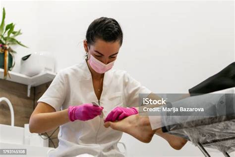 의학 마스크의 페디큐어 마스터는 발톱을 정리합니다 고전적인 페디큐어를 받는 스파 살롱에서 여자 다리 다리와 손톱 스킨 케어 Spa 절차 2명에 대한 스톡 사진 및 기타