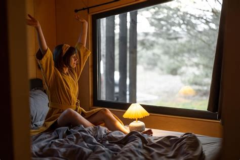 A mulher acorda no quarto minúsculo da cabine de madeira na natureza Foto Premium