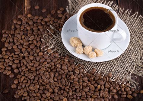 عکس با کیفیت دانه های قهوه در کنار فنجان قهوه و آبنبات های کوچک در کنار