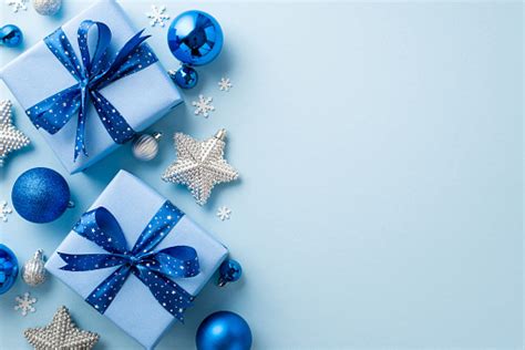 새해 개념입니다 리본 활 파란색과 은색 싸구려가 반짝이는 별 장식품과 빈 공간이 있는 격리된 파스텔 파란색 배경에 눈송이 모양의