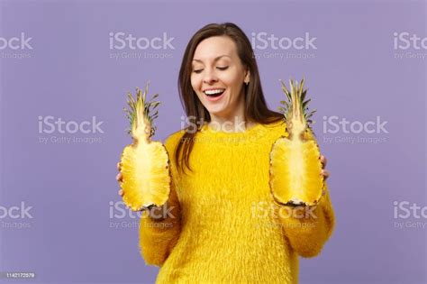 모피 스웨터를 들고 웃는 젊은 여자 보라색 파스텔 벽 배경에 고립 된 신선한 잘 익은 파인애플 과일의 Halfs를 찾고 사람들은 생생한 라이프 스타일 휴식 휴가 개념입니다