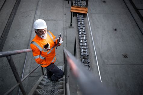 공장 금속 계단에 서있는 안전 유니폼과 하드 햇을 착용하고 태블릿 컴퓨터에서 생산을 확인하는 산업 엔지니어 노동자 관제실에 대한 스톡 사진 및 기타 이미지 Istock
