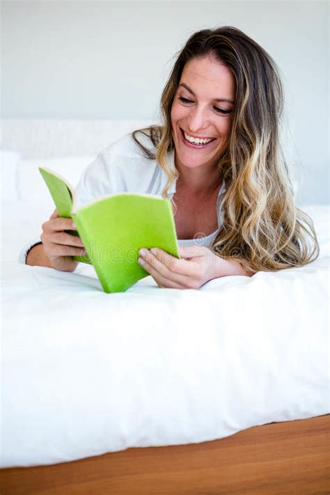 Smiling Woman Lying On Her Bed Reading A Book Stock Image Image Of