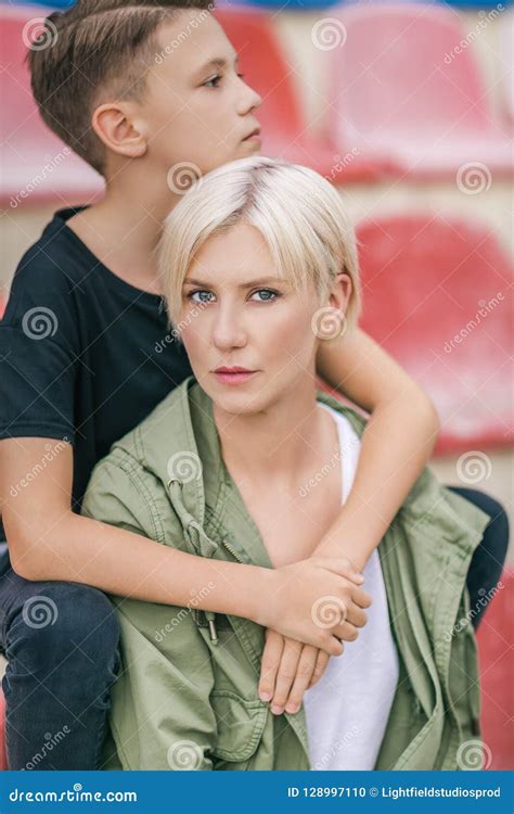 Beautiful Preteen Boy Hugging Mother While Sitting Together Stock Photo Image Of Naturallight