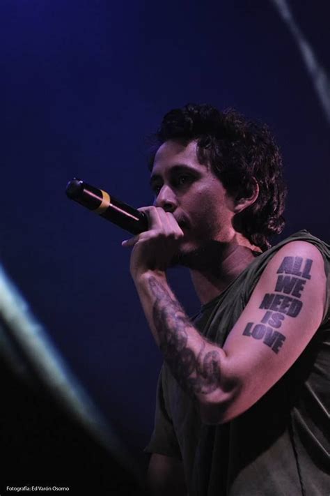 A Man With Tattoos On His Arm Holding A Microphone To His Mouth While