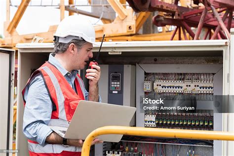 전기 기사 건설 현장 콘솔 캐비닛의 전기 회로 기판 랩톱 컴퓨터를 사용하여 전기 기사 건설 현장에서 전기 시스템 점검 수리 유지 보수 운영 40 44세에 대한 스톡 사진 및