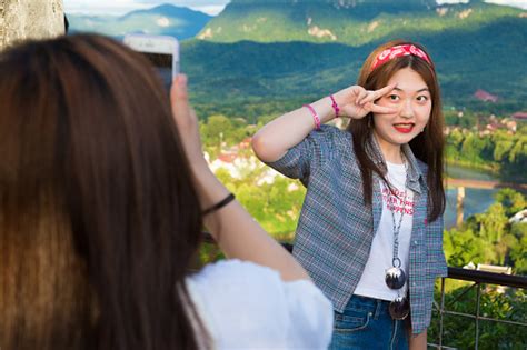 젊은 한국 관광 루앙 피우는 라오스 일몰 전에 포 우시 산 위에 그녀의 친구에 대 한 그림을 걸립니다 관광객에 대한 스톡 사진