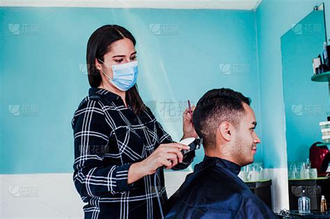 拉丁女发型师，戴面罩，用剪子机和梳子理发。墨西哥男子理发。墨西哥城的理发师服务与covid 19的安