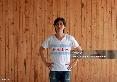 남자는 시카고 국기 컬러 셔츠를 입고 나무 벽 배경에 Akimbo에 서 있었다 국기에 대한 스톡 사진 및 기타 이미지 국기