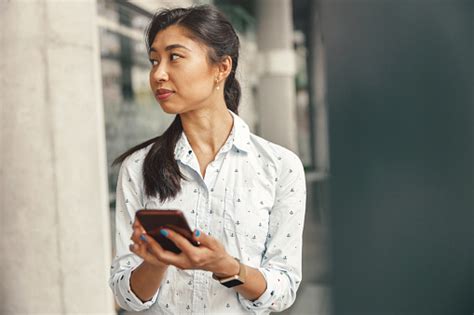 현대 사무실 배경에 스마트폰을 들고 옆을 바라보는 여성 기업가 30 34세에 대한 스톡 사진 및 기타 이미지 30 34세