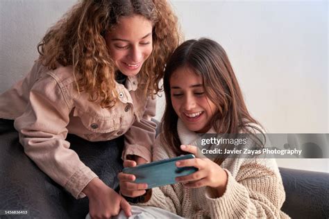 Two Teenage Girls Playing Video Games With A Smartphone At Home Photo