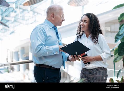 Two Business Women Discussing Business Documents Standing On The