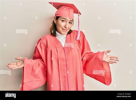 Mujer caucásica joven con gorra de graduación y traje de ceremonia sin