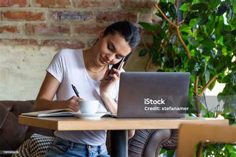 커피숍에 앉아 커피를 마시고 모바일 스마트폰을 사용하는 젊은 여성 테이블에 노트북입니다 소녀 인터넷 검색 채팅 블로그 그녀의