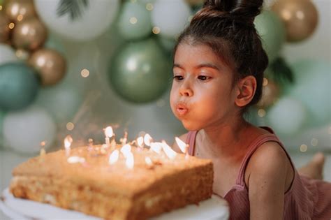 Niña pide deseo y sopla las velas de la tarta de cumpleaños niña celebrando su cumpleaños Foto