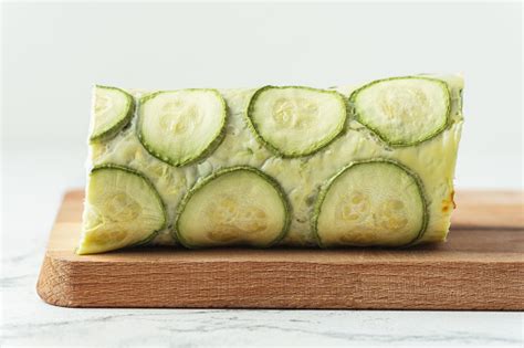 크림 치즈 마늘 및 토마토로 채워진 Zucchini 롤 흰색 배경의 나무 커팅 보드에 녹색 스쿼시 롤 가공 치즈에 대한 스톡