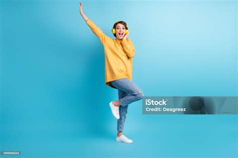 전체 길이 의 몸 크기 측면 프로필 사진 소녀 청취 노래 즐기는 이어폰 은 밝은 파란색 배경에 고립 된 입을 열었다 갈색 머리에