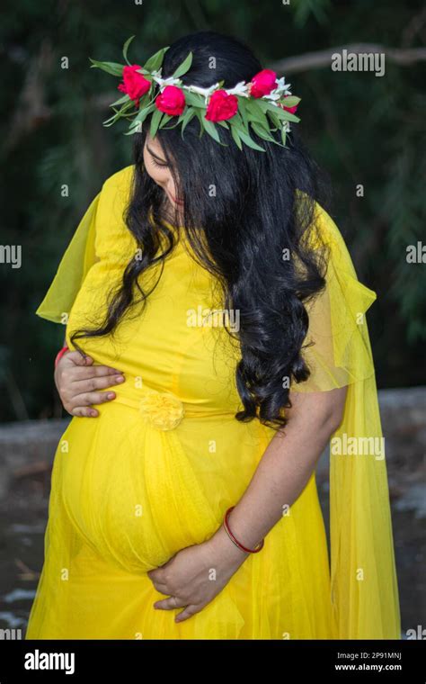 Young Pregnant Women Showing Her Round Belly Womb With Hand In Yellow