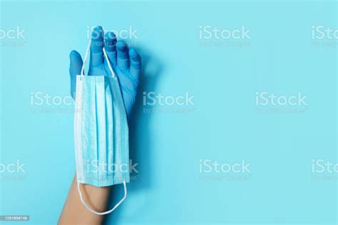 파란색 배경에 의료 용 얼굴 마스크를 들고 파란색 의료 장갑과 손 복사 공간이 있는 배너입니다 검역 중 건강 보호 장비 코로나