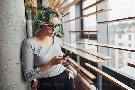 Alternative Girl In Casual Clothes And With Green Hair Standing Indoors
