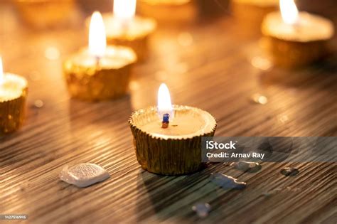 수평 방향의 촛불 배경이있는 나무 테이블에 고립 된 선택적 초점으로 Diwali 밤에 빛나는 불꽃이있는 촛불 Deepavali
