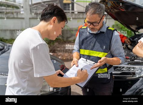 A Car Insurance Agent Showing The Male Customer Where To Sign The Car