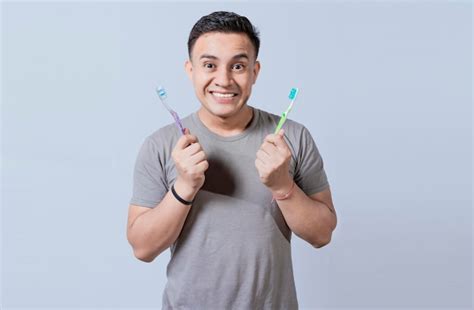 Premium Photo Smiling Guy Holding Two Toothbrushes Isolated Smiling