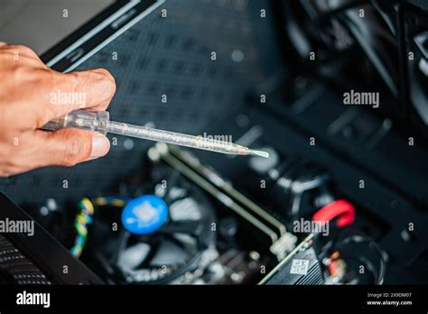 A Person Holding A Thermal Paste Applicator Over An Open Computer Case