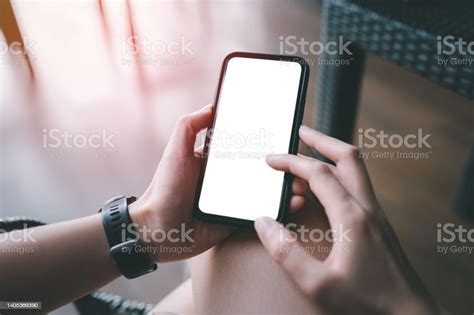 카페 나 커피 숍에서 빈 흰색 화면이있는 모형 휴대 전화를 들고 손 빈 전화 화면은 콘텐츠 또는 광고를 넣고 광고합니다 스마트