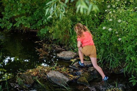 Una Niña Feliz Se Deleita Con La Niñez Mientras Explora Un Arroyo