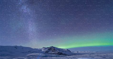 별이 가득한 하늘 아래 눈 덮인 경사면 위에 서있는 사람 사진 Unsplash의 오로라 이미지