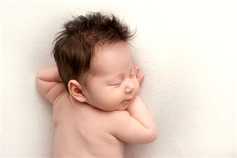 Vista superior de una niña recién nacida acostada sin ropa en una cama