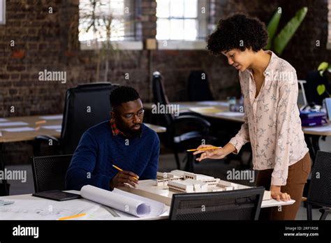 diverse male and female architects looking at building model and