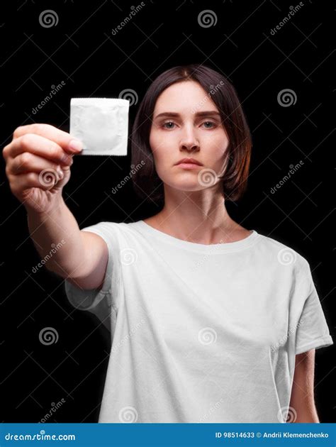 Uma Jovem Mulher Séria Que Mostra Um Preservativo Embalado Em Um Fundo