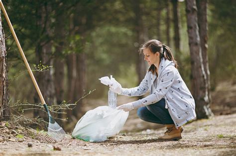 캐주얼 옷 공원 또는 숲 녹색 배경에 쓰레기 봉투에 쓰레기를 청소 장갑에에서 젊은 여자 환경 오염 문제입니다 자연 쓰레기 환경