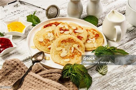 흰색 접시에 아몬드 꽃잎과 맛있는 팬케이크 맛있는 전통 아침 식사 흰색 소박한 배경에 잼 팬케이크 흰색 식기 제공 달콤한 디저트