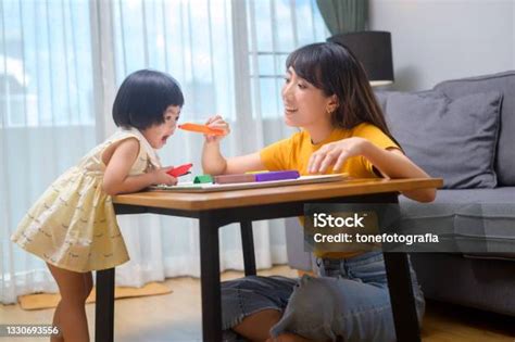 Ibu Muda Membantu Putri Menggambar Dengan Pensil Berwarna Di Ruang Tamu