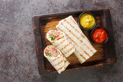 아랍 전통 음식 Shawarma 나무 보드에 소스와 야채 근접 촬영과 샌드위치를 롤드 수평 상단 보기 부리토에 대한 스톡 사진