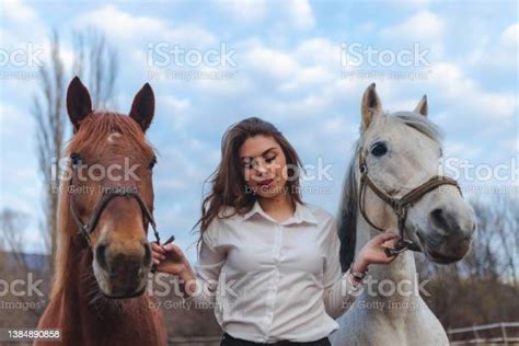시골에서 말 두 마리와 함께 걷는 흰색 셔츠를 입은 젊은 백인 여성 18 19세에 대한 스톡 사진 및 기타 이미지 18 19세 가축 농부 Istock