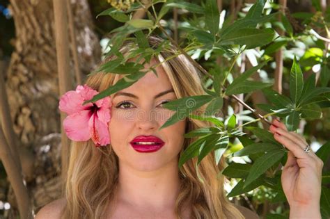 Portrait Of A Beautiful Blonde Woman With A White Shirt And A Hibiscus